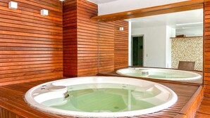 Casa de banho com painéis de madeira, um espelho grande e uma banheira com divisória de vidro.