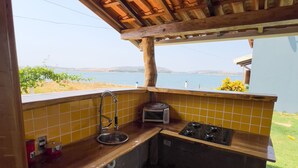 Cozinha com vista para um lago, fogão a gás, pia e micro-ondas.