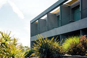 Um edifício moderno com varanda, cercado por diversas plantas.