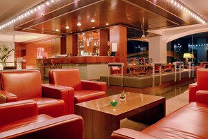 Um lobby moderno com assentos de couro, uma mesa de recepção e um bar.