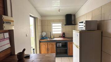 Cozinha compacta com armários de madeira, micro-ondas embutido e geladeira.