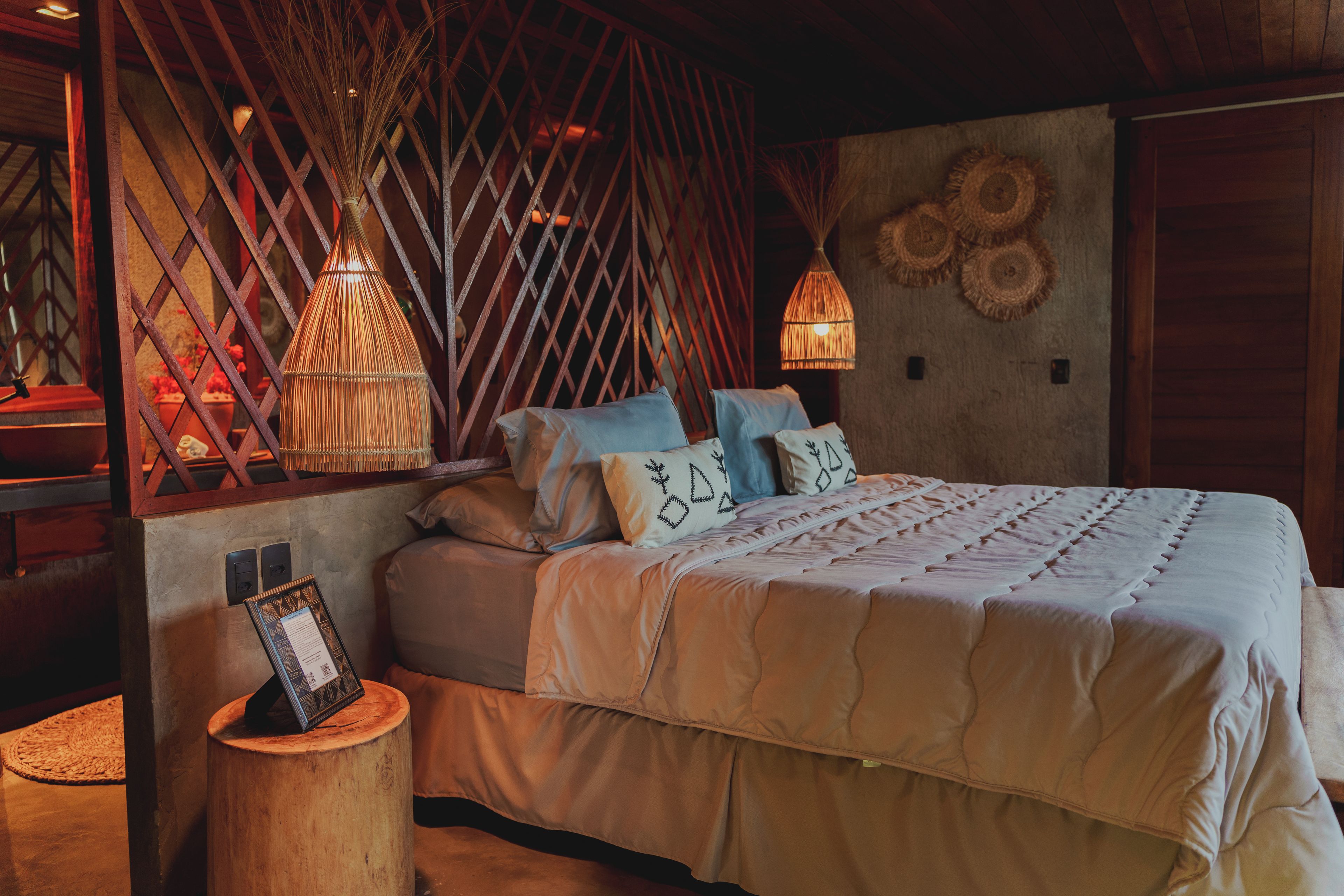 Quarto com cama, cabeceira de madeira e adornos decorativos na parede.