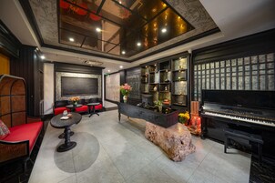 Ampla sala de estar com piano, assentos e um detalhe decorativo na parede.