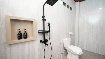 Casa de banho moderna com chuveiro, sanita e prateleira com dois frascos de champô e gel de banho.