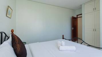 Quarto de hotel com uma cama, cabeceira de madeira, guarda-roupa e um quadro na parede.