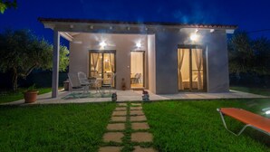 Uma casa moderna com varanda, área externa para sentar e um caminho até a entrada.