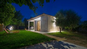 Uma casa moderna com varanda, gramado e um caminho de brita.