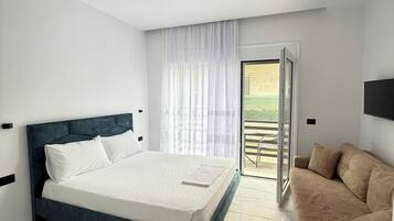Quarto moderno com uma cama grande, um sofá e uma porta de vidro deslizante que dá para uma varanda.