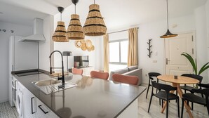 Cozinha moderna com ilha central, cadeiras pretas e mesa de jantar.