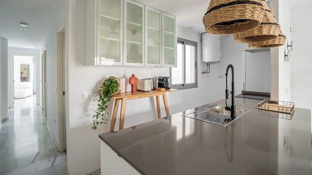 Uma cozinha moderna com uma ilha central, uma mesa de madeira e um pendente tecido.