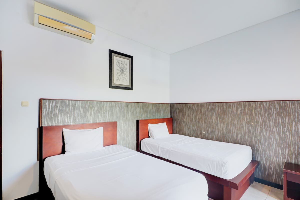 Quarto de hotel com duas camas, uma obra de arte emoldurada na parede e um aparelho de ar condicionado.