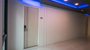 Um corredor com uma porta marcada '301', uma luminária moderna e um chão revestido de azulejos.