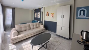 Quarto de hotel moderno com sofá, uma mesinha, guarda-roupa e obras de arte nas paredes.