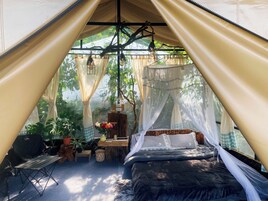 Uma tenda com uma cama, uma mesa e plantas em vasos.