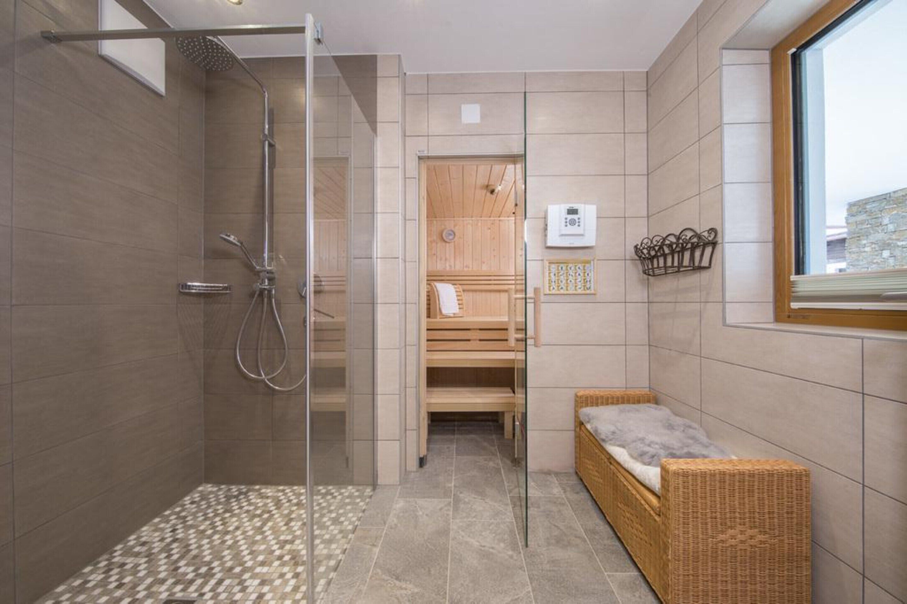 Um banheiro moderno com chuveiro em cabine de vidro, sauna de madeira e um banquinho de vime.
