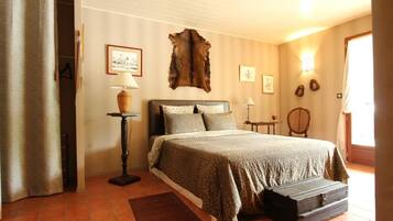 Quarto com cama, mesa de cabeceira, luminária, mala e tapete de pele fixado na parede.