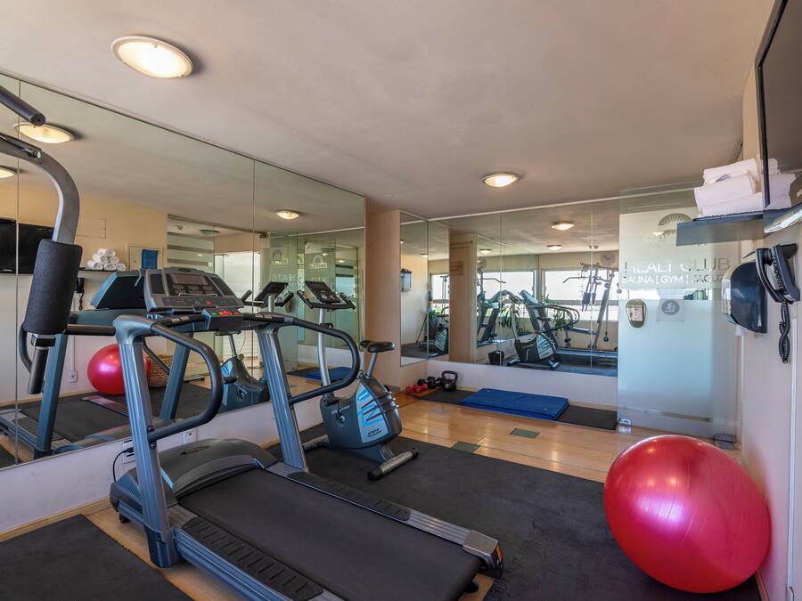 Academia com esteiras, bolas de exercício e espelho.