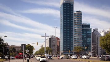 Um cruzamento urbano movimentado com edifícios altos, semáforos e pedestres.