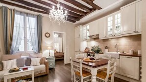 Uma cozinha moderna com armários brancos, uma mesa de jantar com cadeiras e um candelabro.