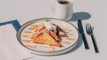 Um prato de comida com sobremesa, uma xícara de café e um cardápio sobre a mesa.