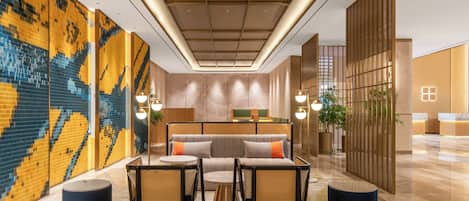 Um lobby moderno com área de estar, balcão de recepção e um painel decorativo.