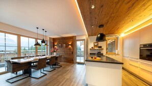 Cozinha moderna com ilha central, piso de madeira e iluminação pendente.