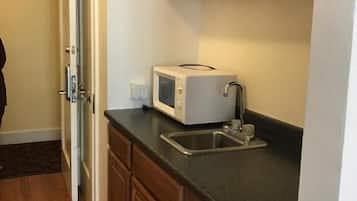 Uma cozinha compacta com armários de madeira, micro-ondas, pia e geladeira.