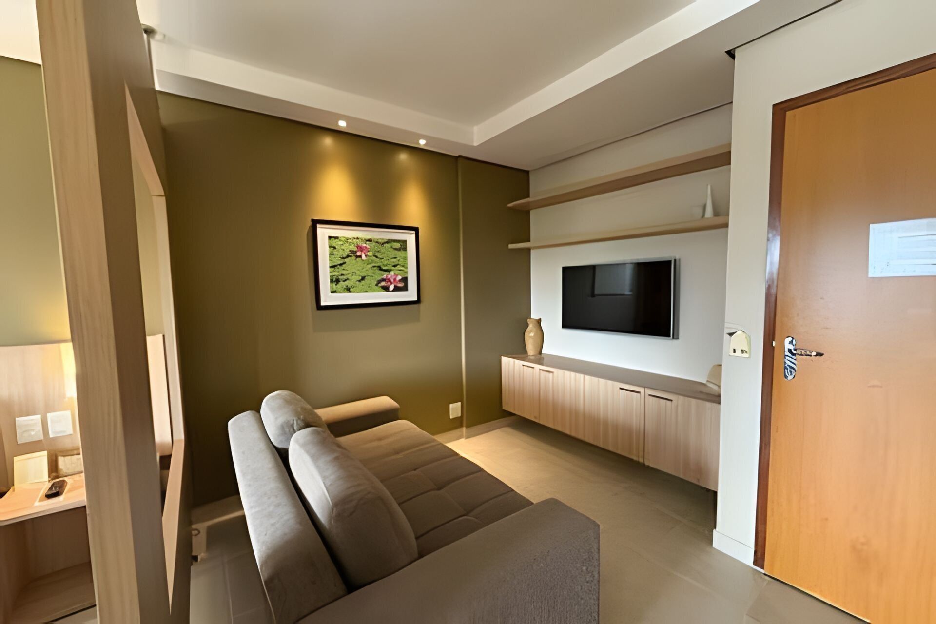 Uma sala de estar moderna com sofá, televisão na parede e porta de madeira.