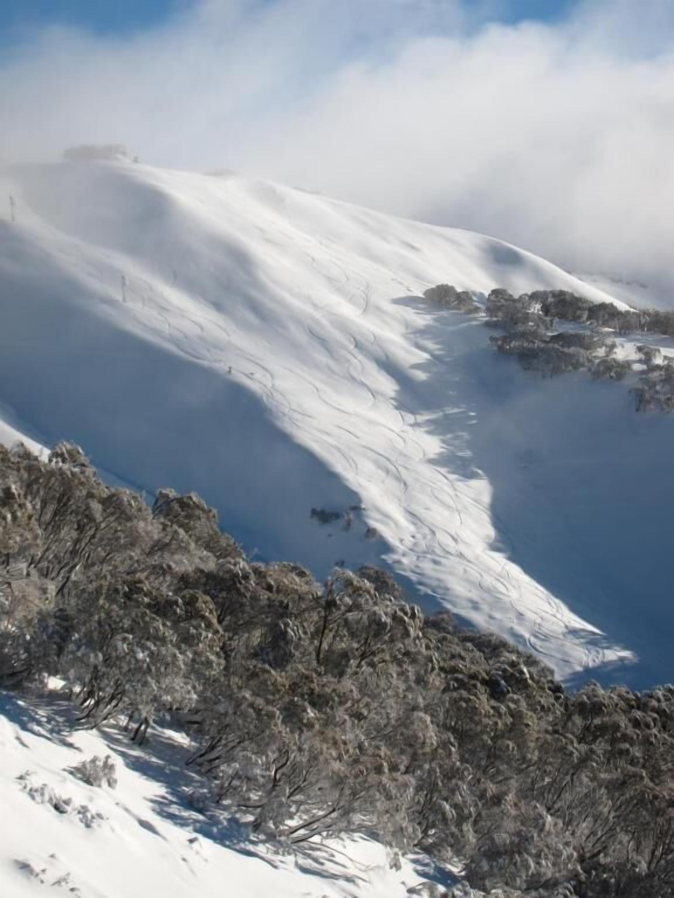 Montanha coberta de neve, com primeiro plano rochoso e céu limpo.