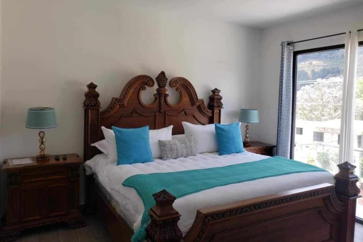 Quarto com cama de madeira, duas mesas de cabeceira e uma janela com vista.