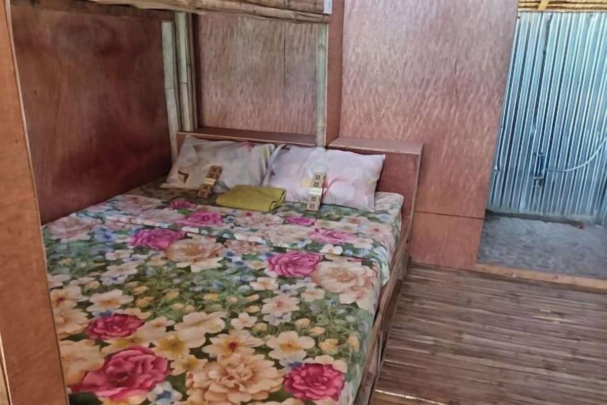 Quarto com cama de madeira, roupa de cama floral e portão de metal.