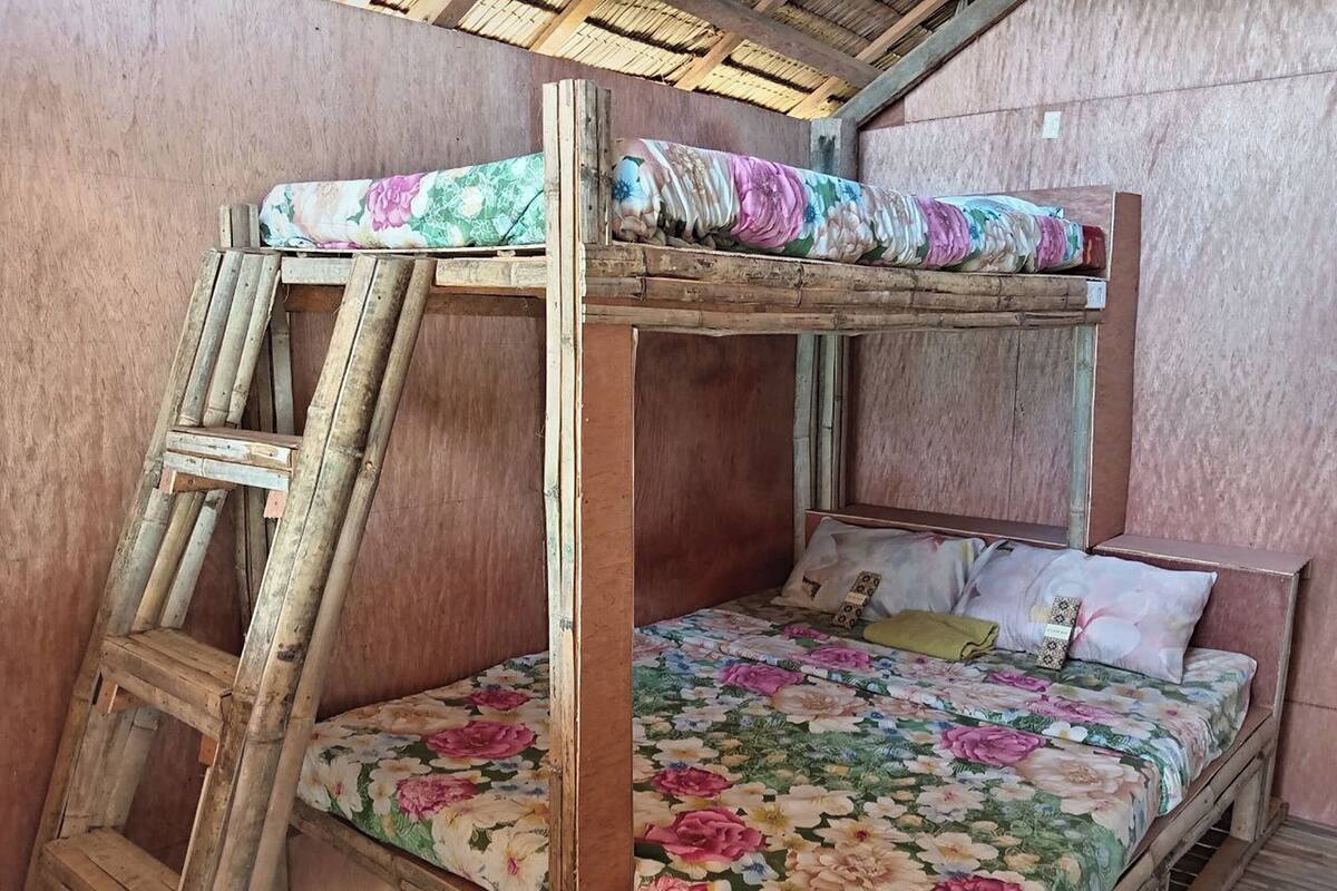 Uma cama beliche com escada, roupa de cama florida e cabeceira de madeira.