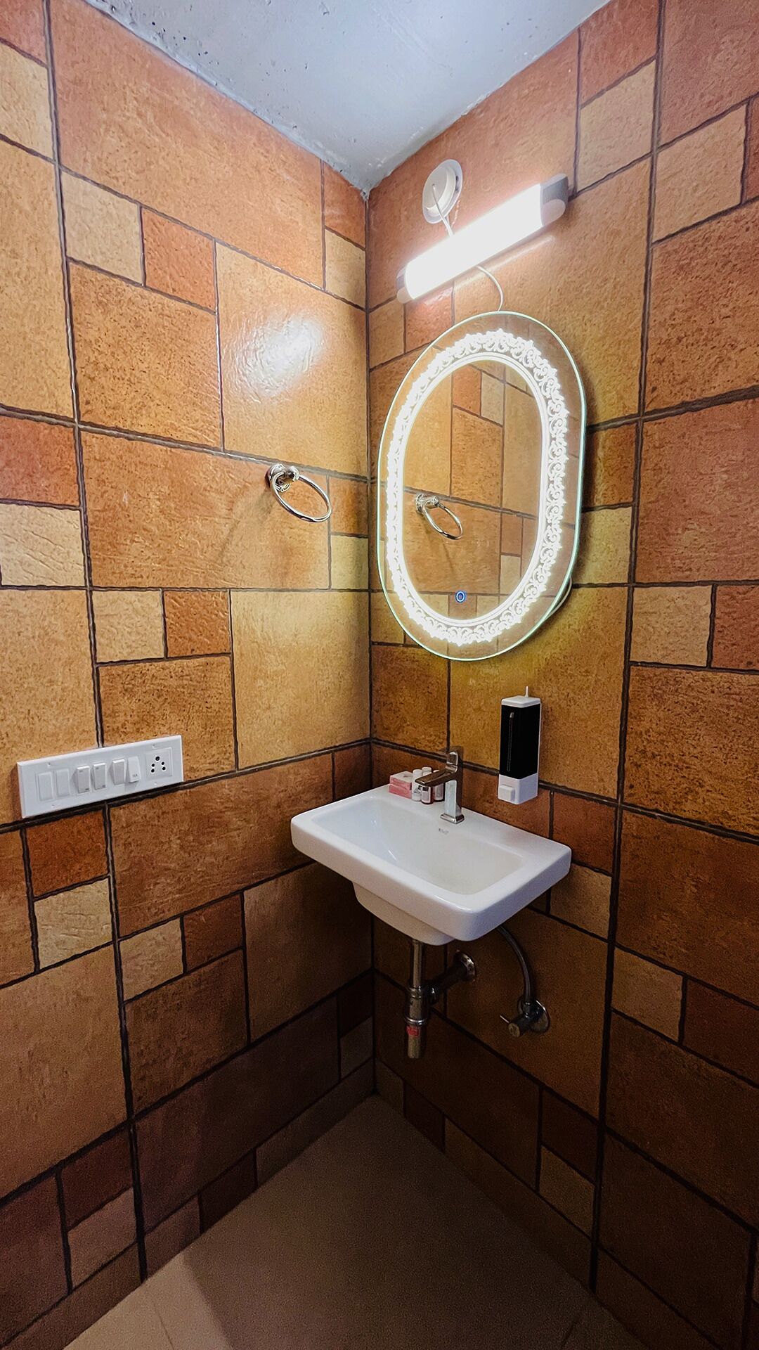 Um banheiro com pia branca, espelho com moldura decorativa e dispensador de sabonete.