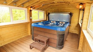 Uma cabana de madeira com hidromassagem, soalho de madeira e janelas.