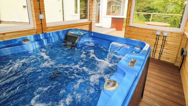 Uma banheira de hidromassagem em uma cabana de madeira com vista para o exterior.