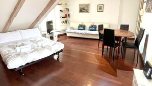 Um quarto estilo loft com cama, mesa de jantar com cadeiras, sofá e estante.