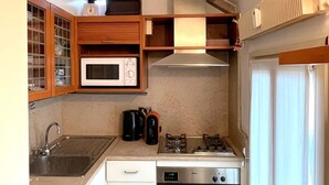Uma cozinha compacta com micro-ondas, fogão, forno e máquina de café.