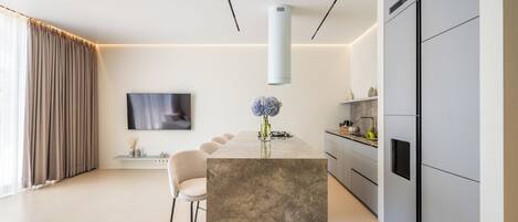 Uma cozinha moderna com uma ilha central, uma TV de tela plana na parede e um forno embutido.