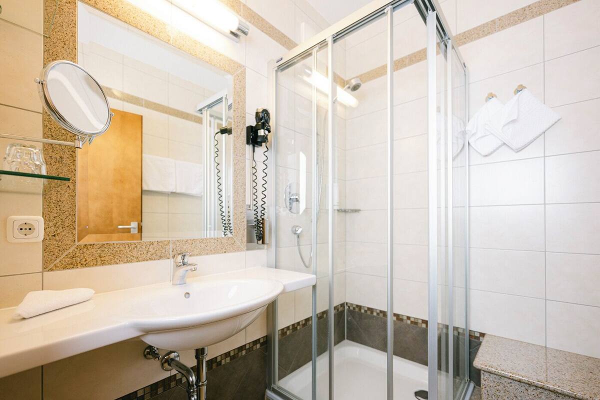 Um banheiro moderno com box de vidro, pia com espelho e porta-toalhas.
