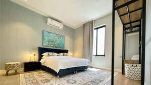 Quarto moderno com cama grande, tapete decorativo, mesa de cabeceira e janela com cortinas.