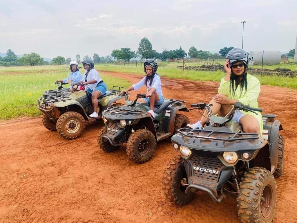 Três pessoas pilotando veículos todo-terreno em uma trilha de terra.