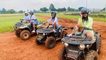 Três pessoas pilotando veículos todo-terreno em uma trilha de terra.