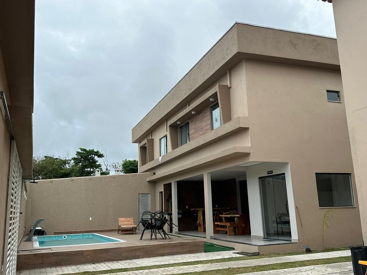 Um edifício moderno de dois andares com piscina, área de estar externa e um alpendre coberto.