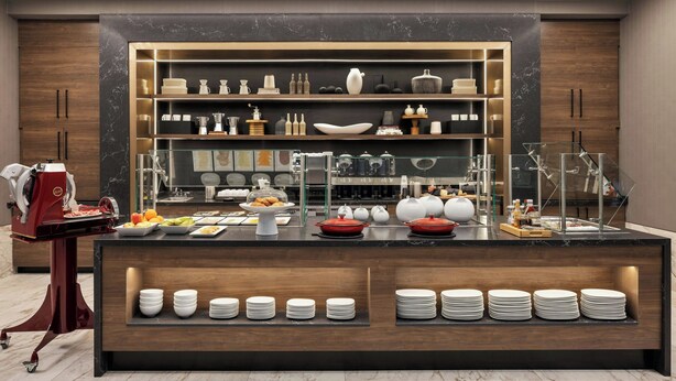Uma cozinha moderna com bancada de mármore, vitrines de vidro e pratos e tigelas organizados.