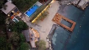Vista aérea de uma propriedade com piscina, deck de madeira e muro de pedra.