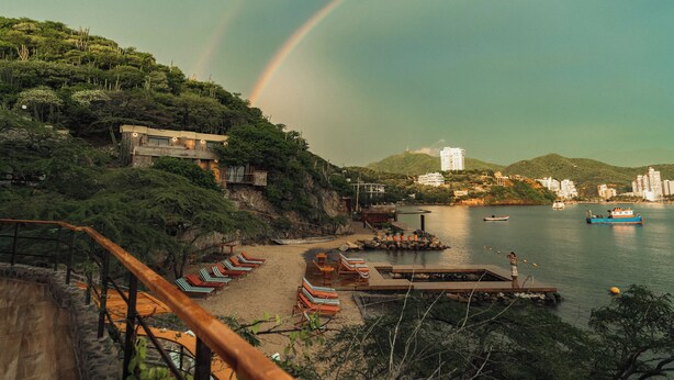 Uma praia com espreguiçadeiras, um píer e barcos na água.