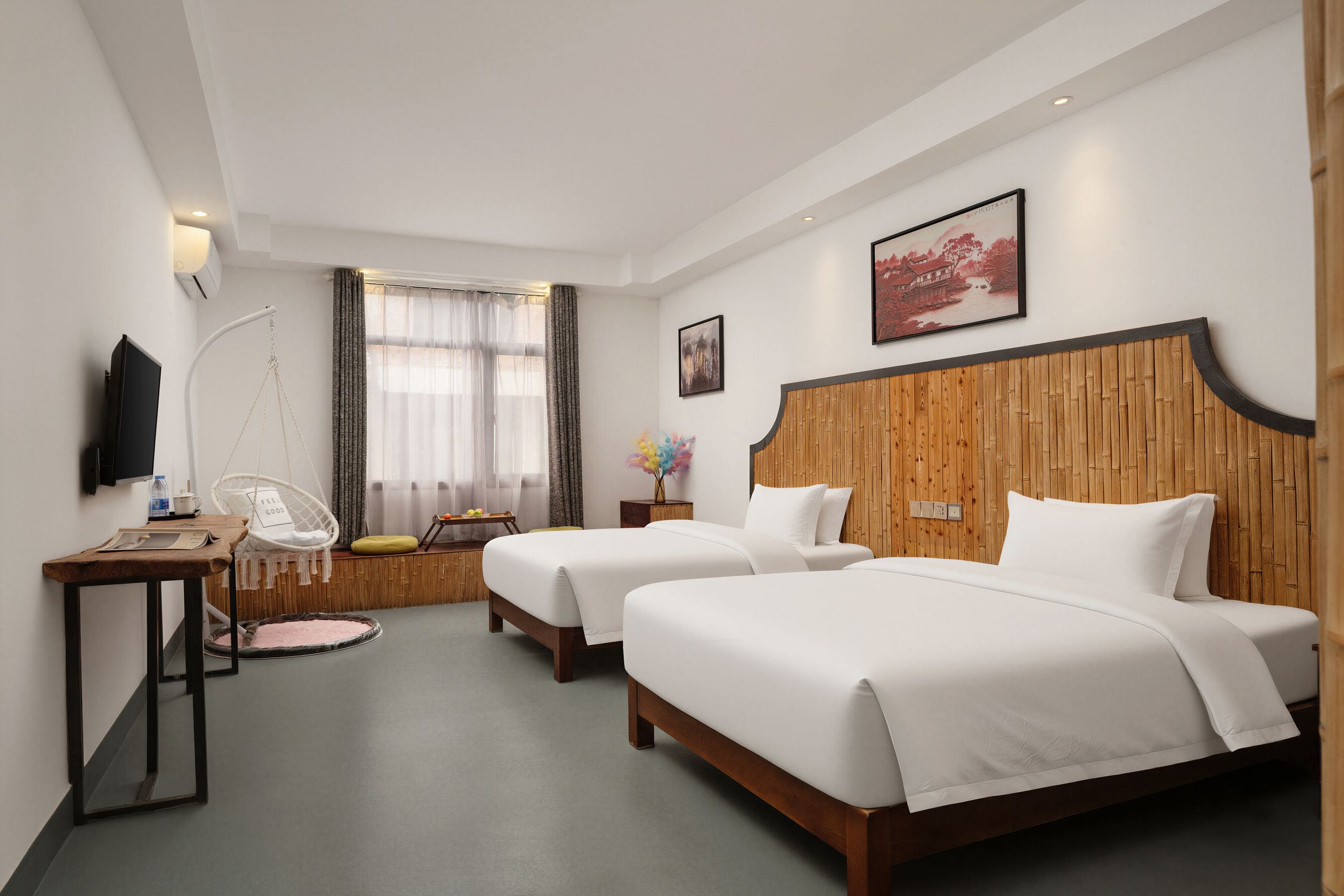 Quarto de hotel com duas camas, uma mesa, uma cadeira, uma televisão e uma janela com cortinas.