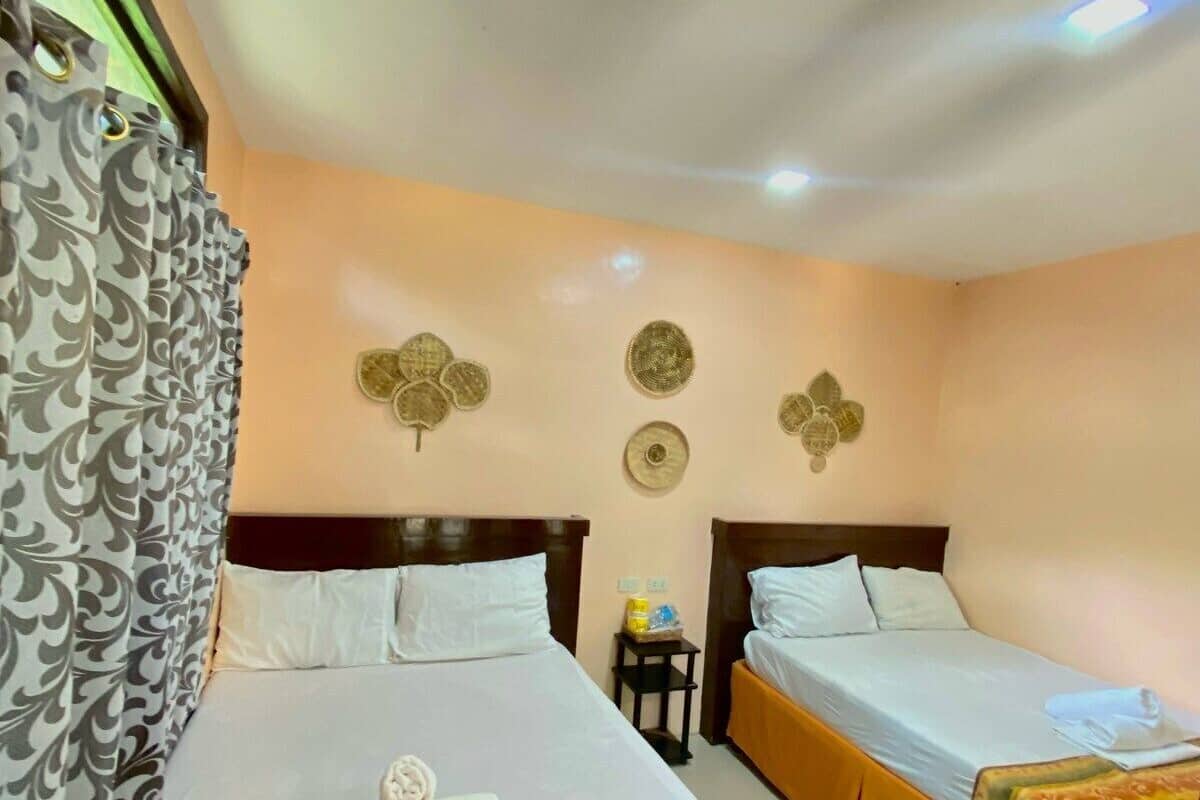 Quarto de hotel com duas camas de solteiro, uma cama grande e uma cortina.