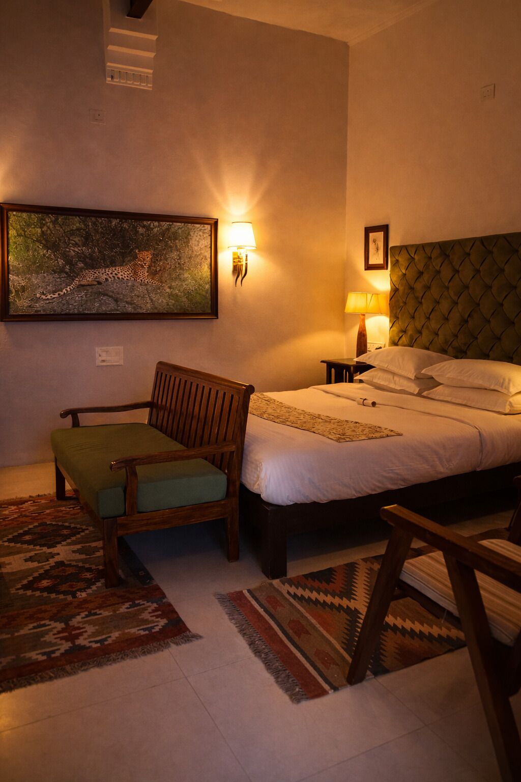 Quarto com cama, cadeira, tapete, luminária na parede e um quadro.