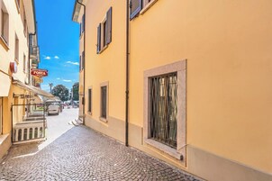 Uma rua estreita de paralelepípedos com edifícios de ambos os lados, um letreiro de restaurante e uma van estacionada.